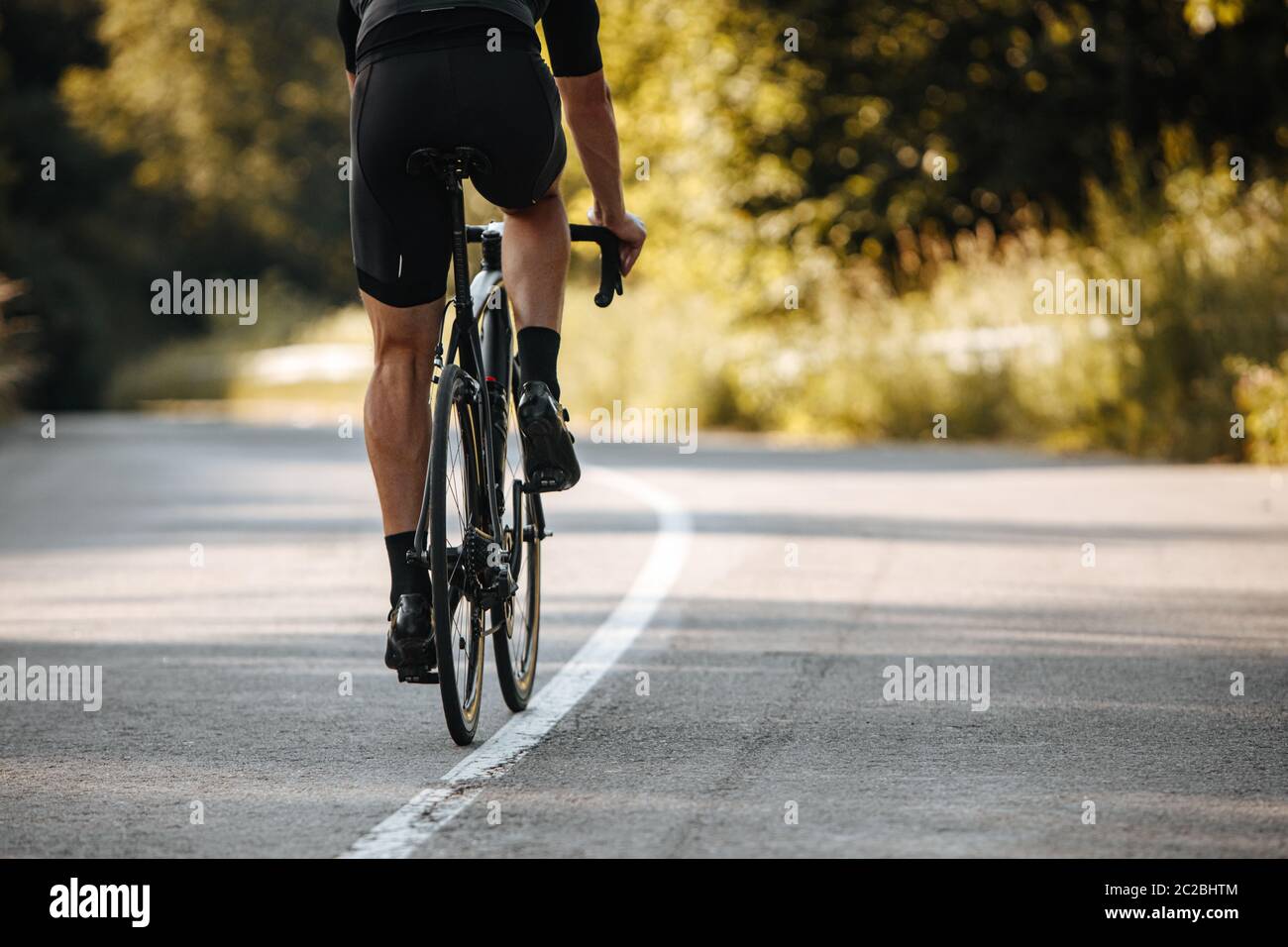 Back view of cyclist in activewear riding professional bike on paved ...