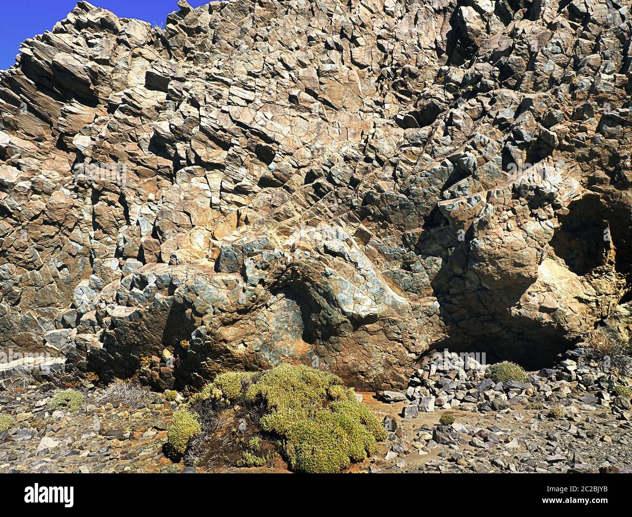 A high natural lava stone wall, consisting of colorful cuboid segments ...
