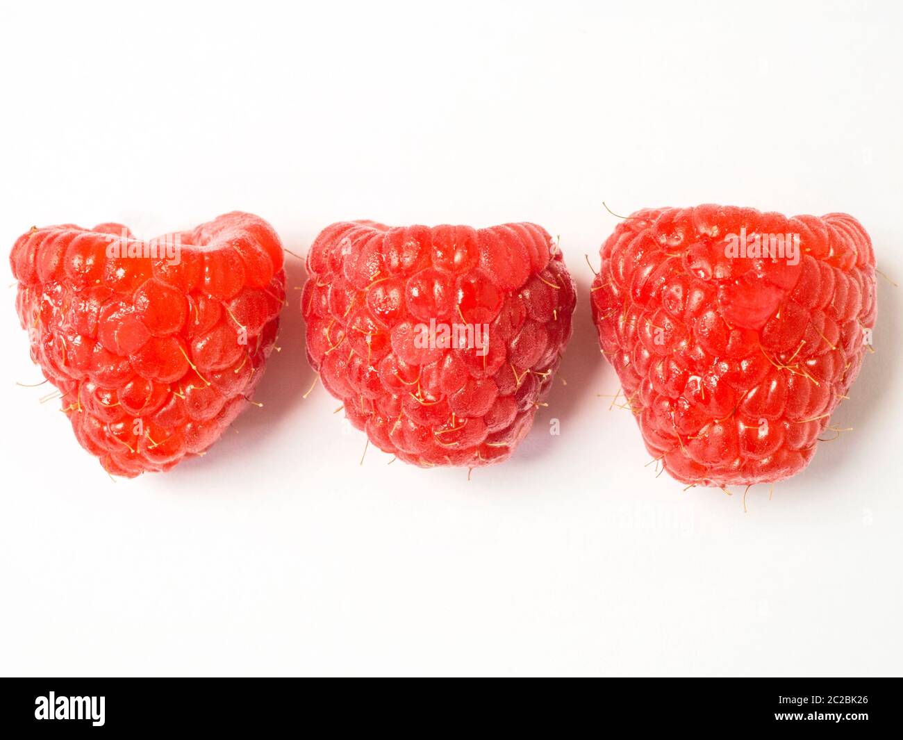 Three ripe raspberries on a white background with copy space above and ...