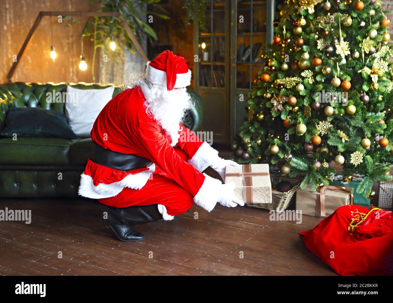 Santa Claus secretly putting gift boxes under the Christmas tree Stock ...