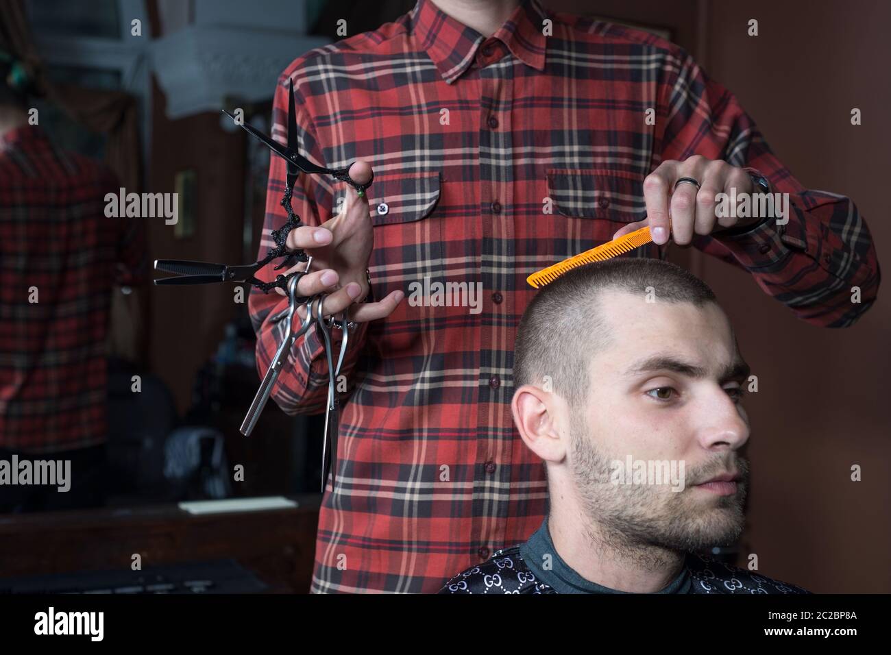 hairdresser a young guy with many scissors in his hand, cuts with a ...