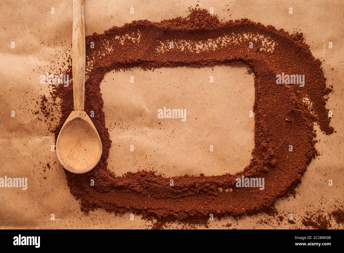 wooden spoon with ground coffee in the shape of a rectangle on a brown ...