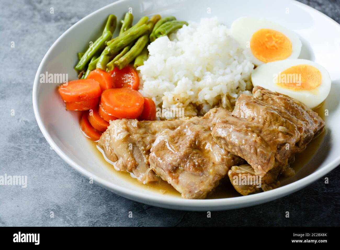Baked pork ribs with rice, boiled egg and vegetable Stock Photo - Alamy