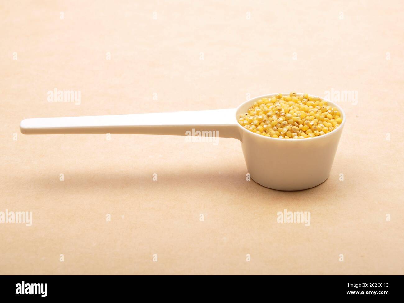 Raw millet in measuring spoon on brown background Stock Photo - Alamy