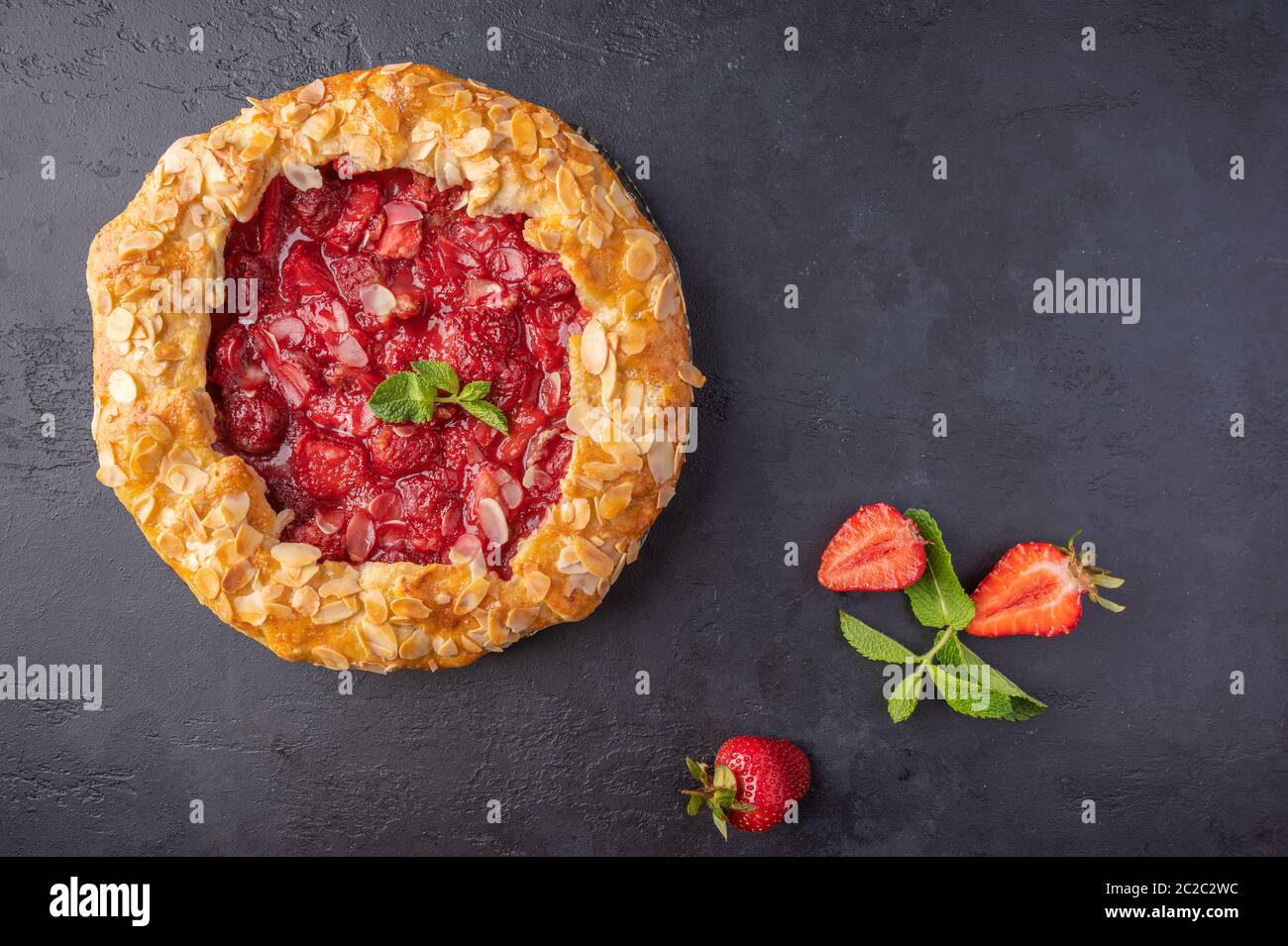 Homemade summer flan pie with strawberries. mint and almond petals on ...