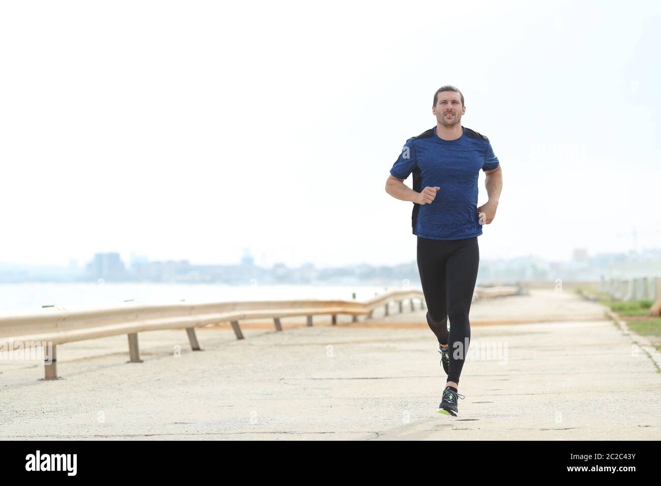 Front view portrait of runner running towards camera on the beach Stock ...