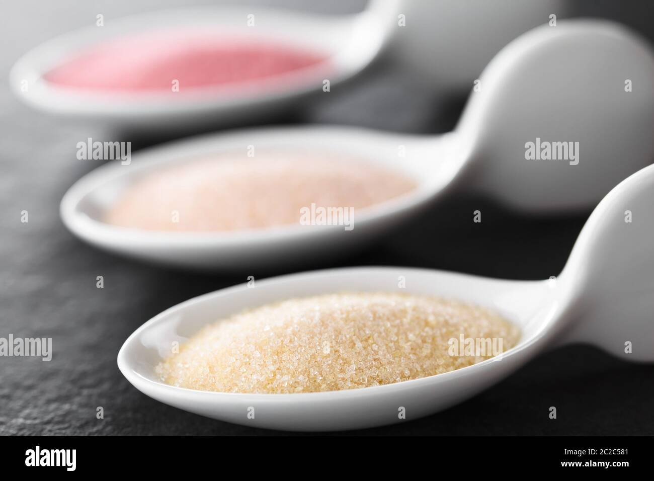 Yellow, orange and red instant jelly or jello powders on small spoons ...