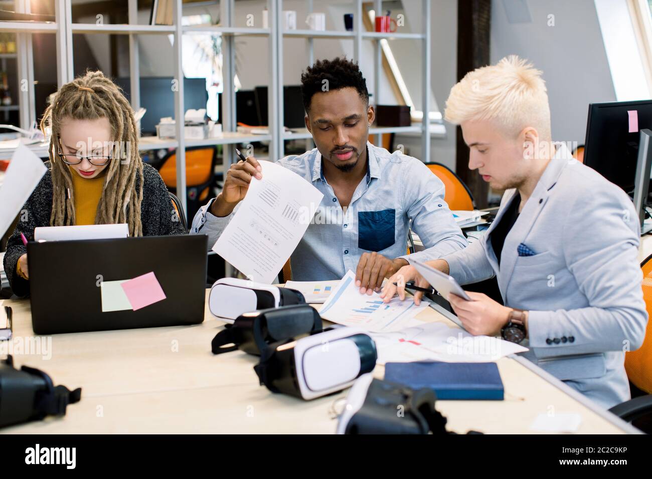 Office life, teamwork. Three young multiethnical business people, blond ...