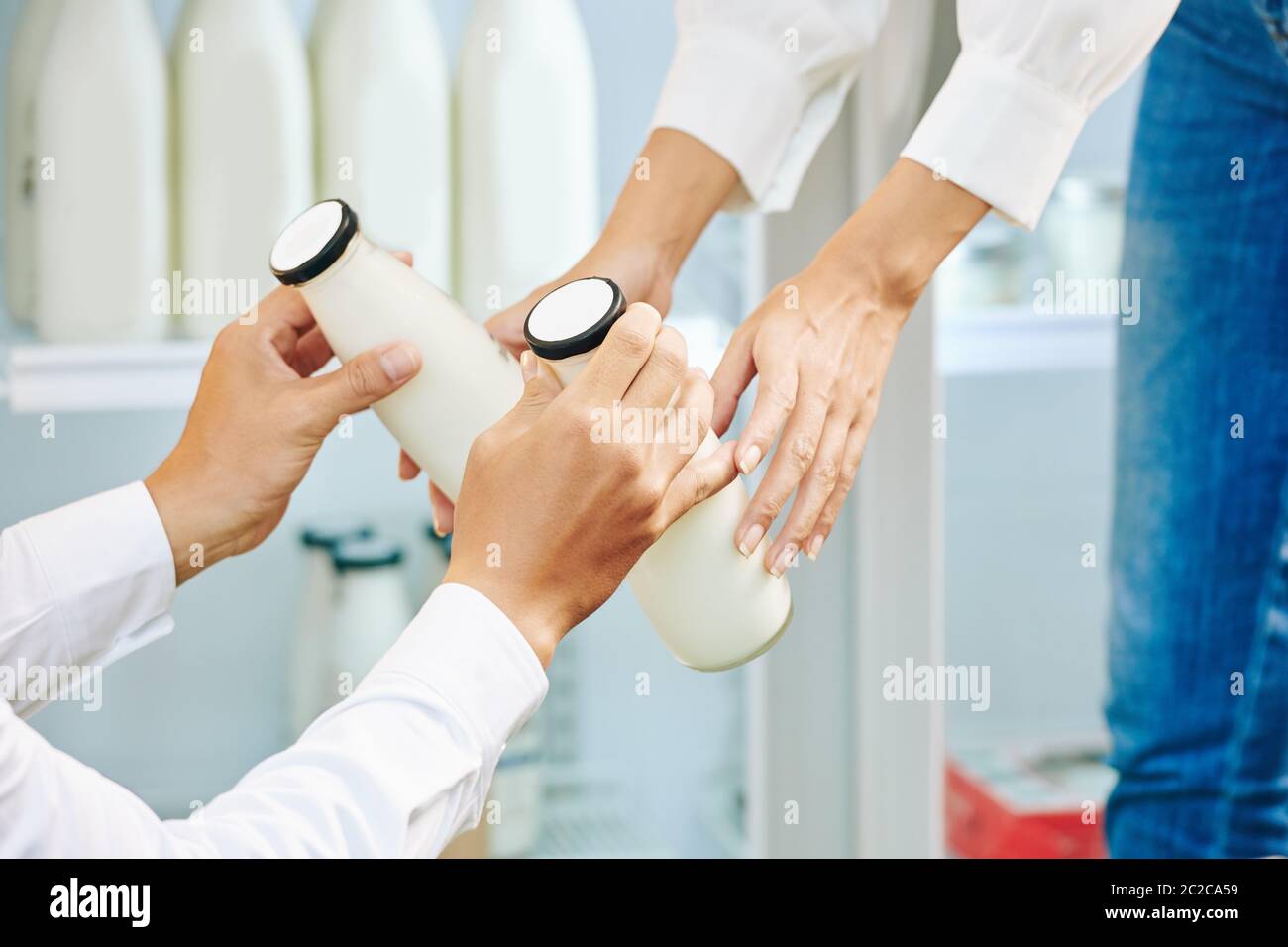 Horizontal close up shot of hands giving and taking two glass bottles ...