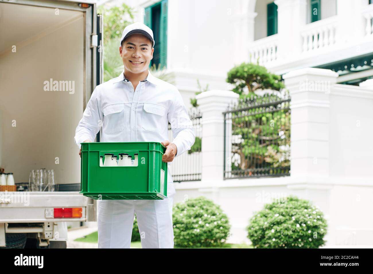 Horizontal medium long portrait shot of modern milkman wearing white ...
