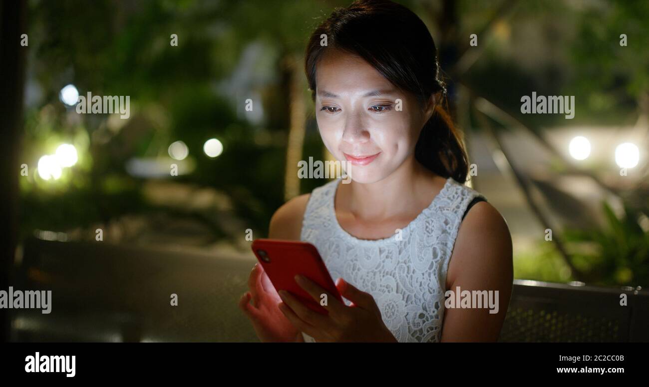 Woman use of mobile phone in the city at night Stock Photo - Alamy