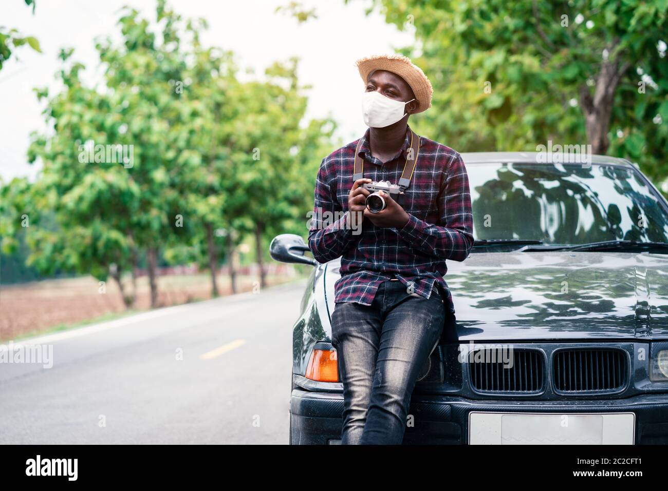 African man traveler is standing near car freelancing on the road with ...