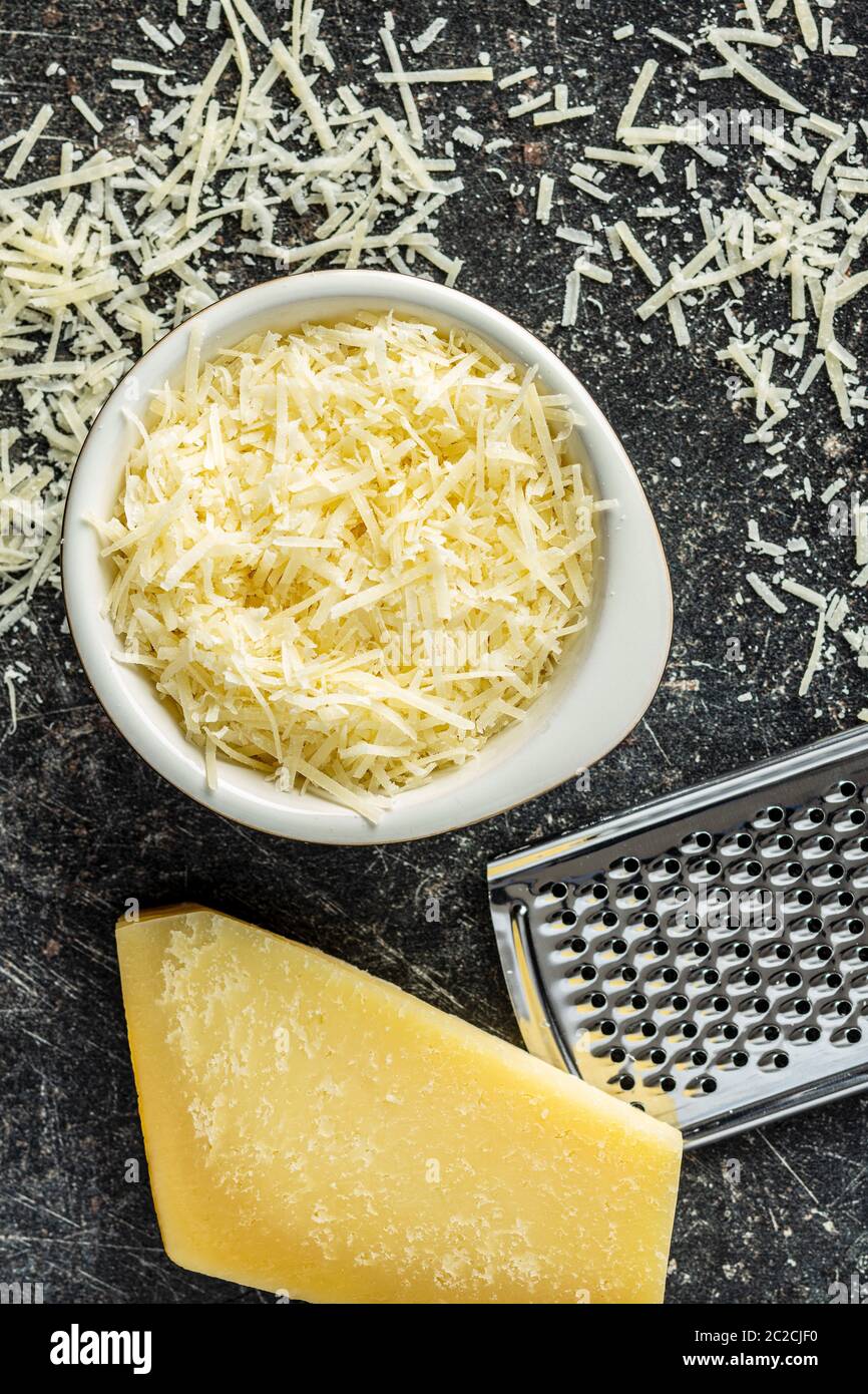 Tasty grated cheese. Parmesan cheese on old kitchen table. Top view ...