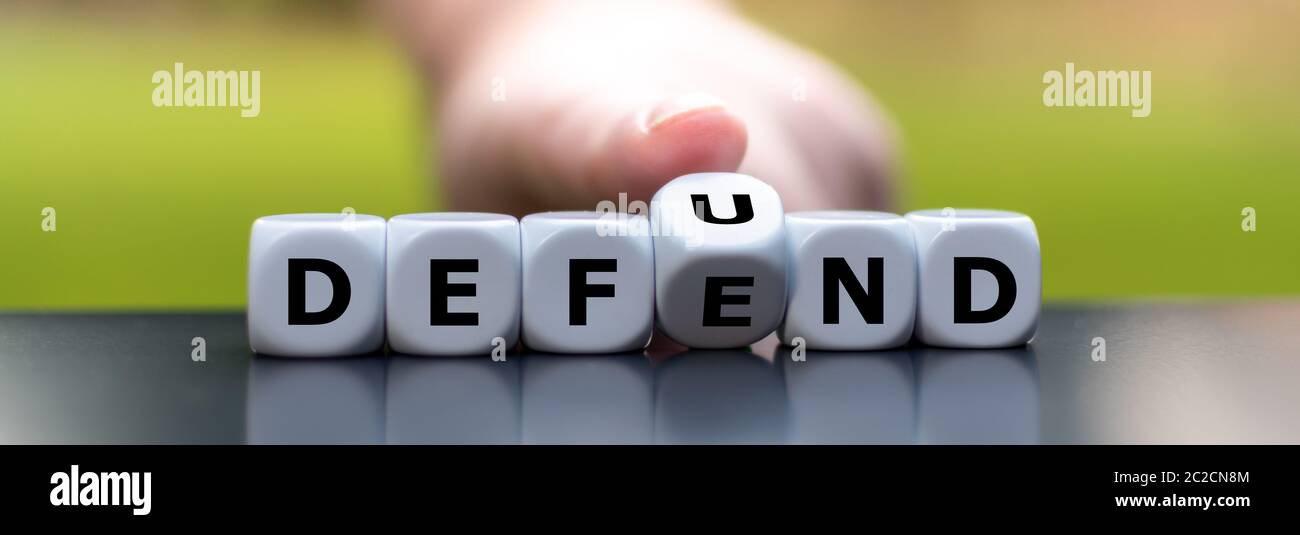 Hand turns dice and changes the word "defend" to "defund Stock Photo ...