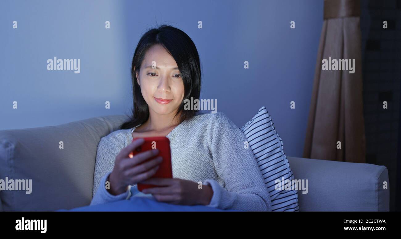 Woman lying down on sofa and use of mobile phone at home Stock Photo ...