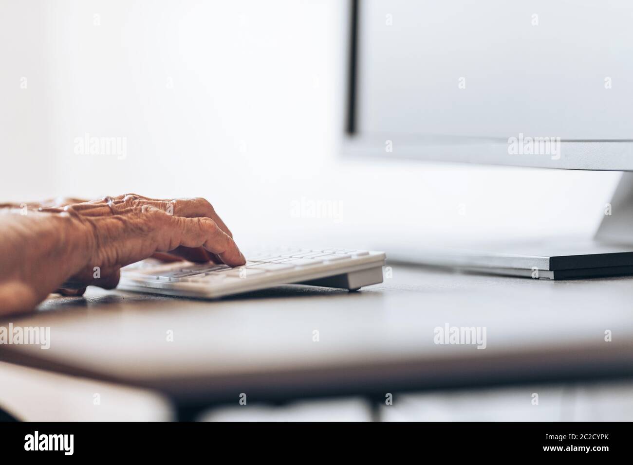 Elderly woman typing on a PC keyboard Stock Photo - Alamy
