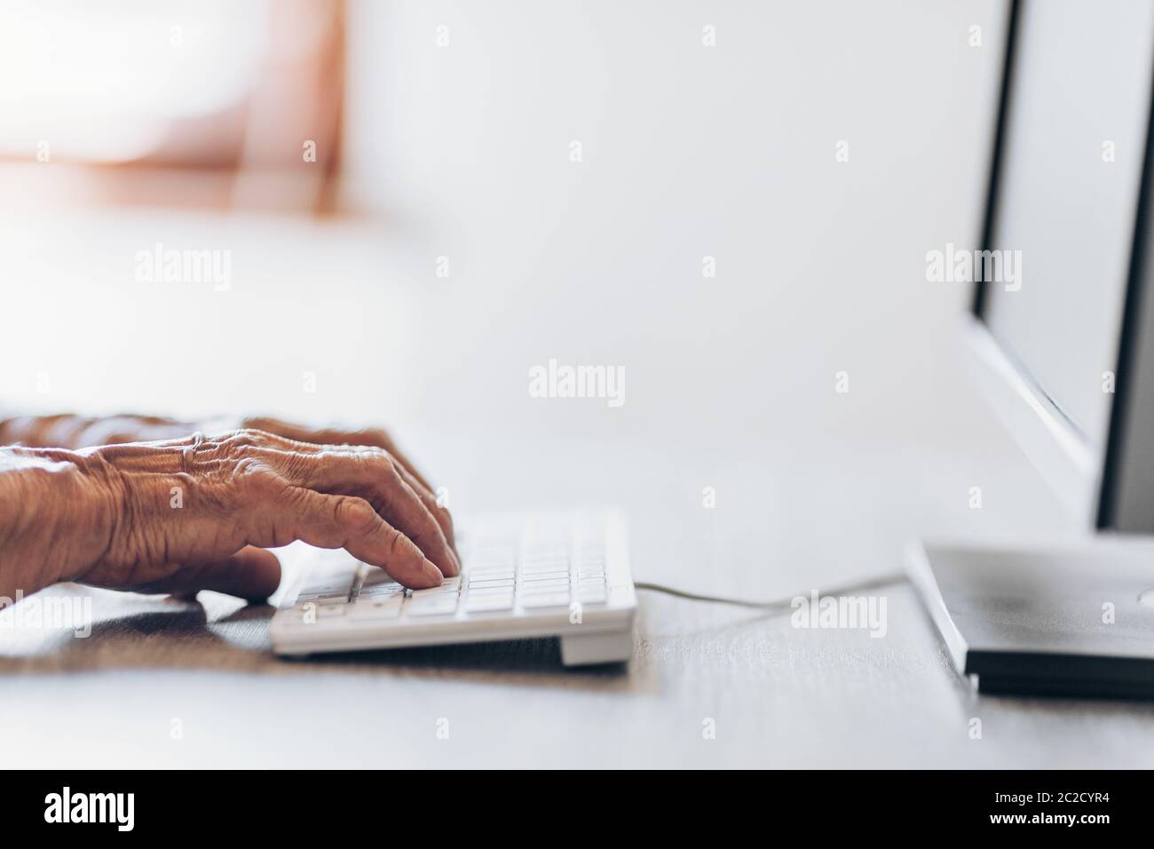 Elderly woman typing on a PC keyboard Stock Photo - Alamy