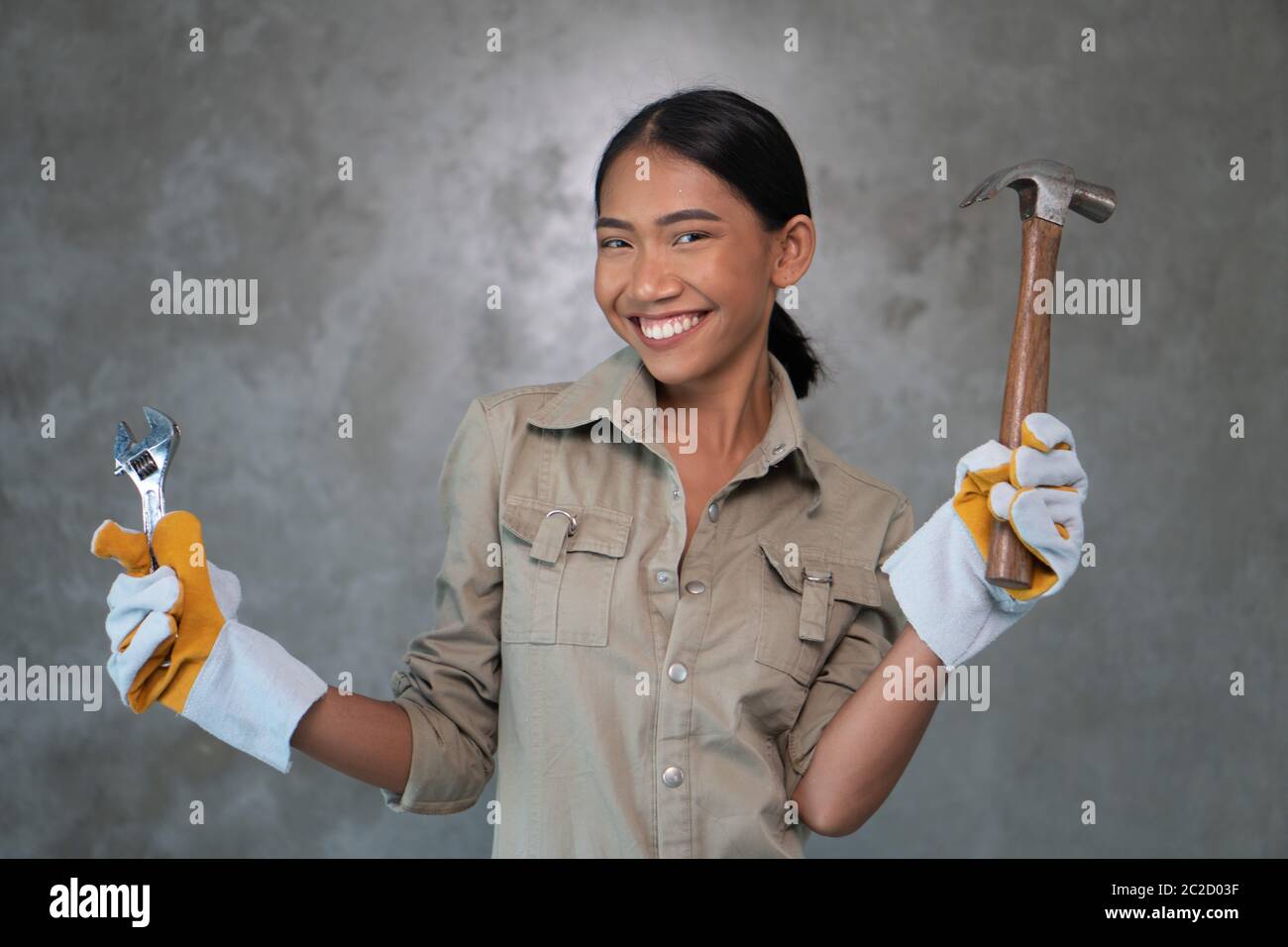 Portrait of attractive young girl builder wrench and hammer in overall ...