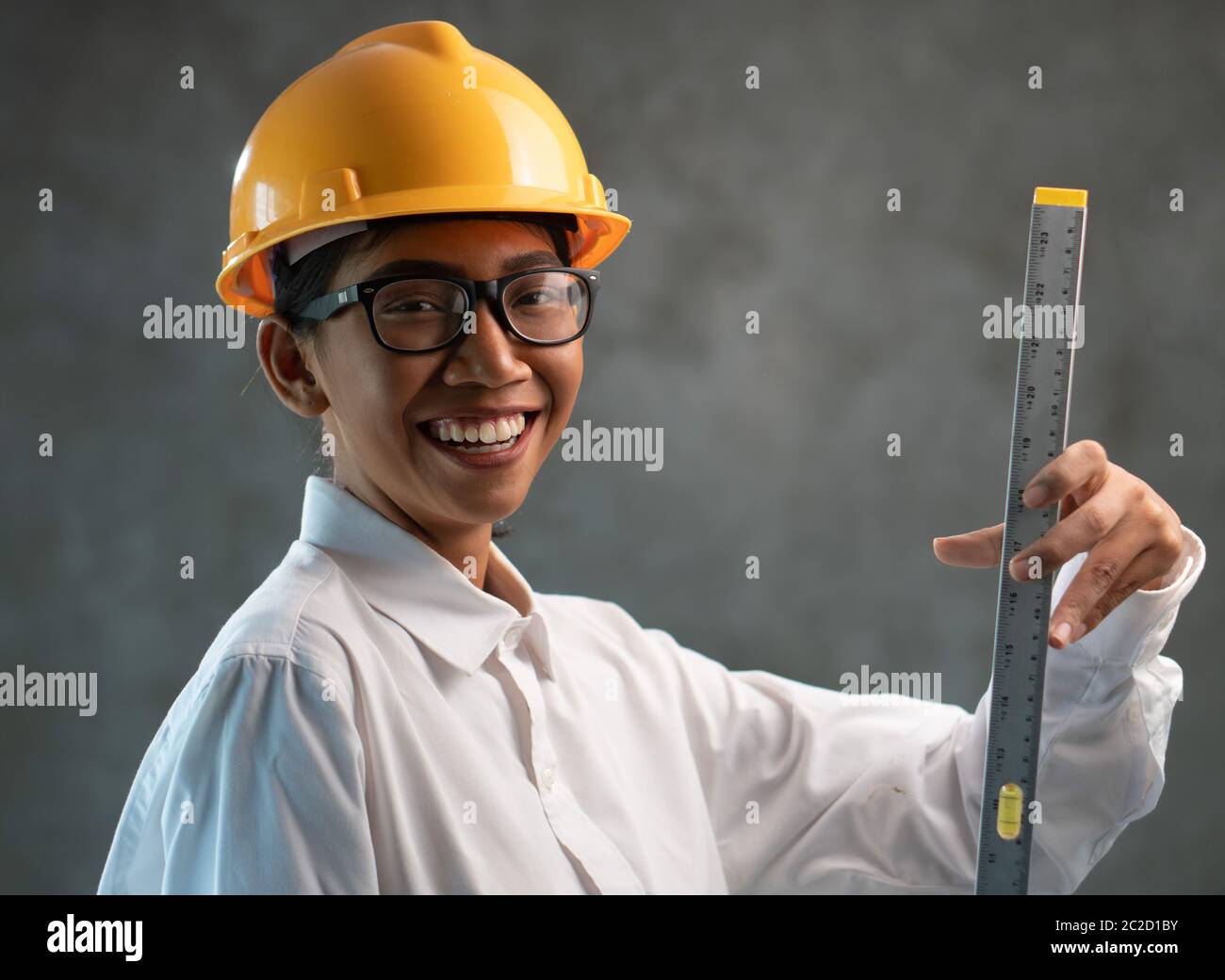 Portrait of attractive Asian woman engineer with building level over ...