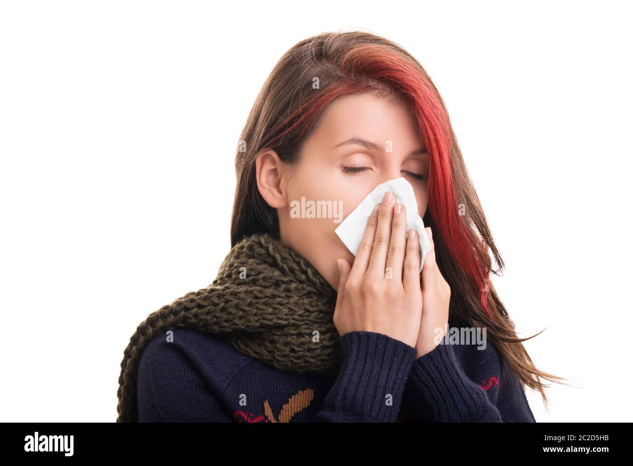 Cold and flu season. Portrait of a girl in winter clothes blowing her ...