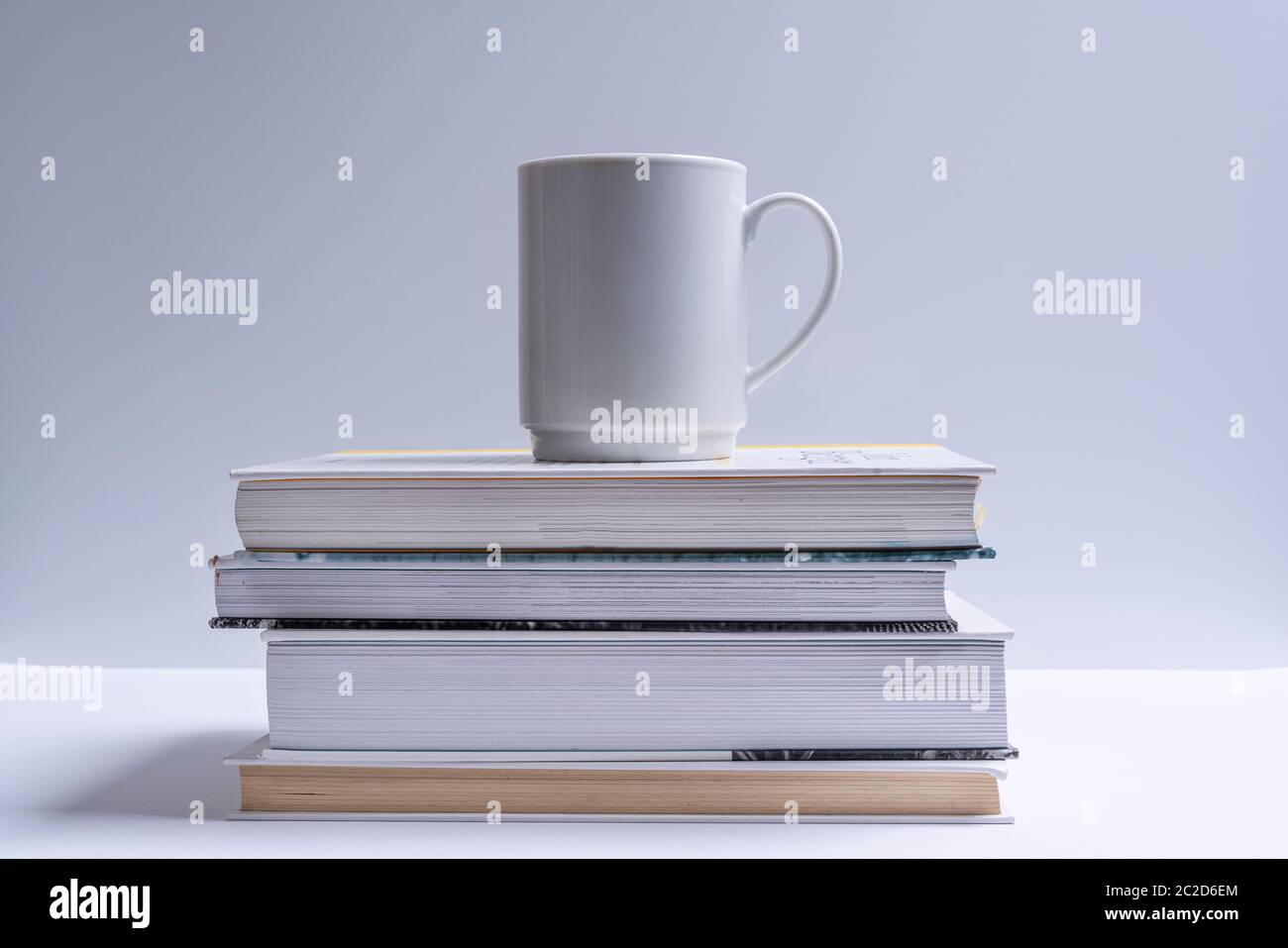 A white cup of coffee over a stack of books Stock Photo - Alamy