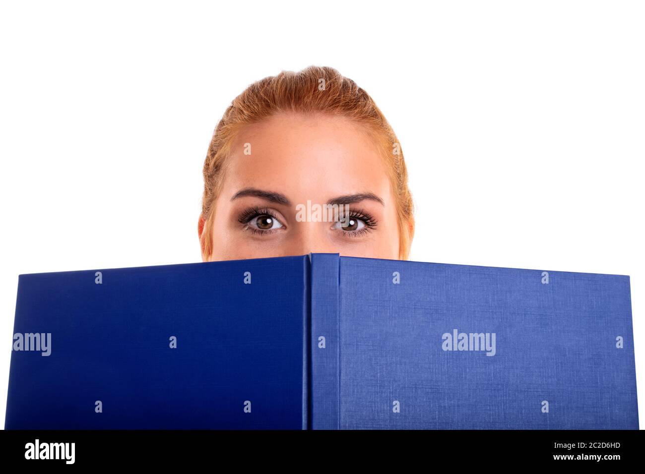 Close-up shot of a young girl covering half of her face with a book ...