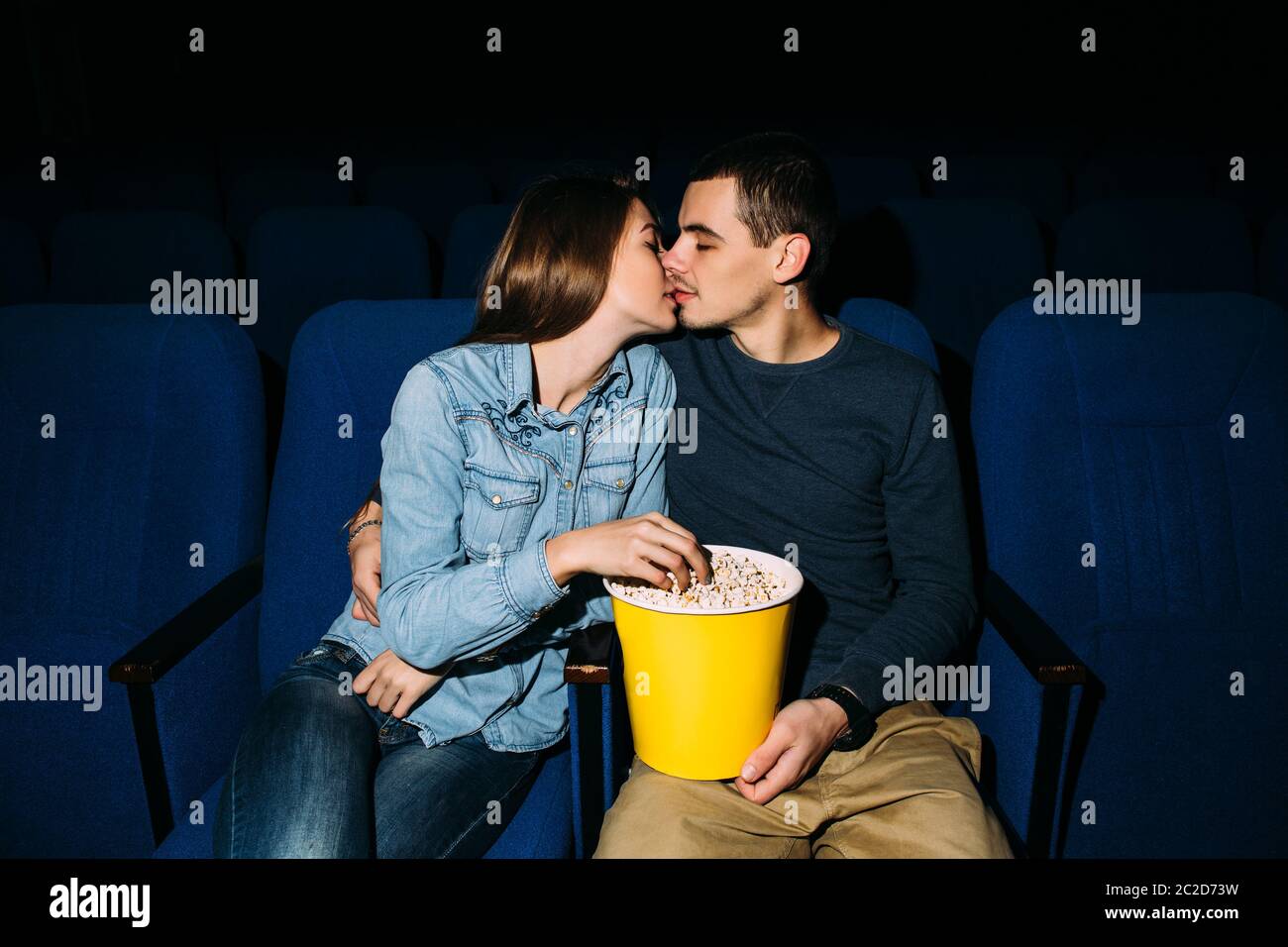 Cinema day. Young beautiful couple kissing while watching romantic ...