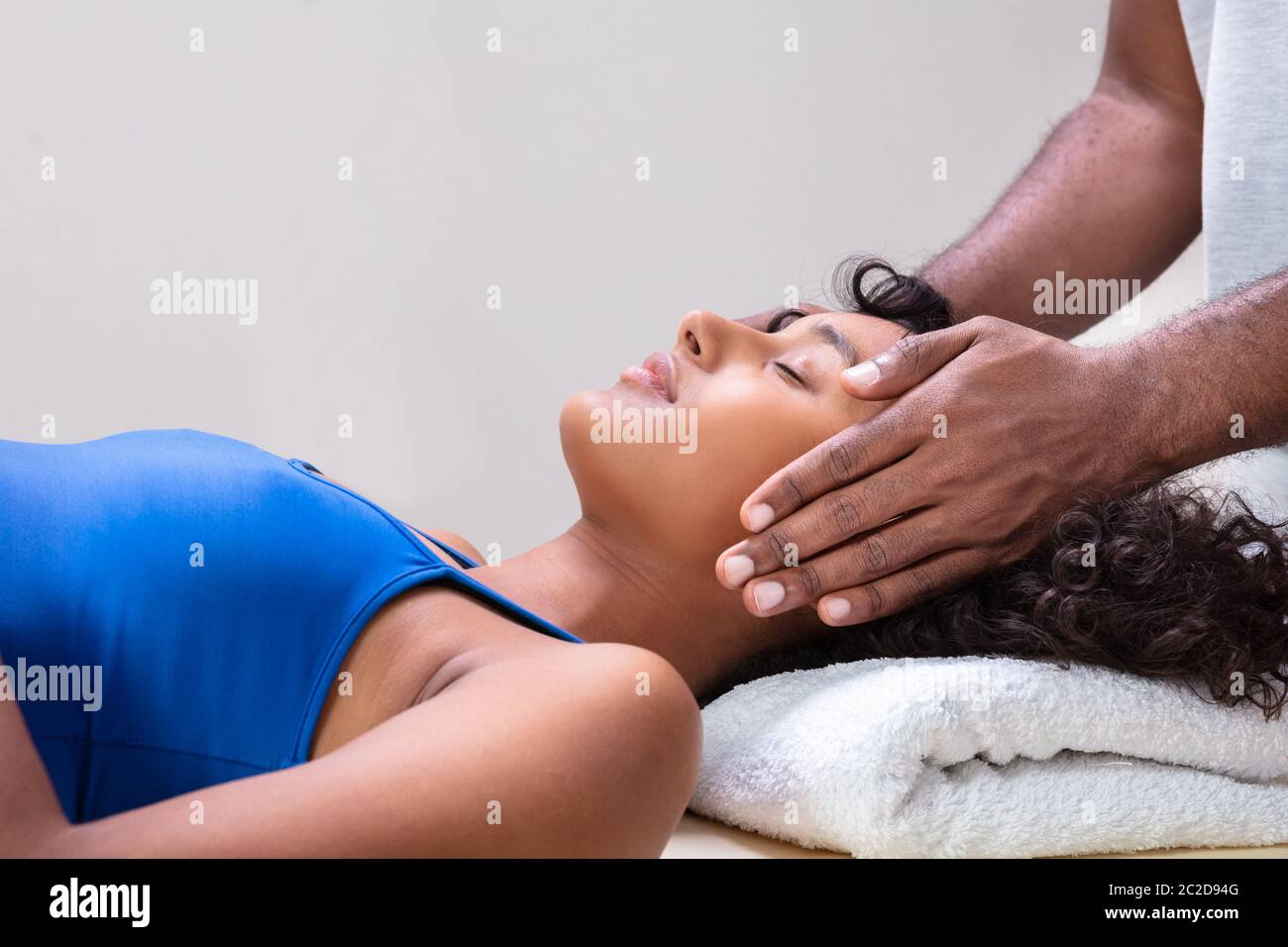 Close Up Of Therapists Hand Performing Reiki Treatment On Young Woman