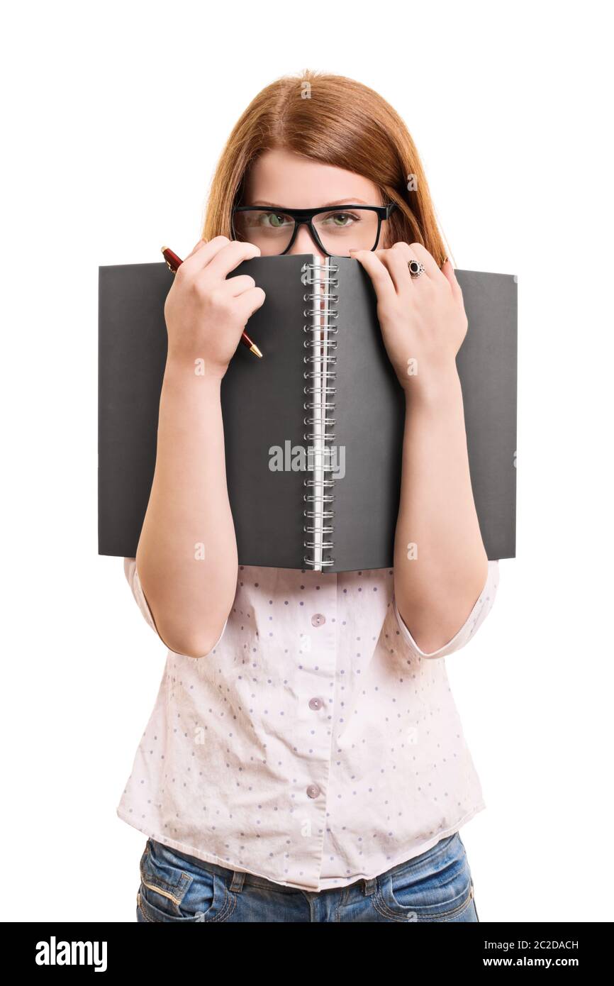 A portrait of a young female student hiding behind her book, isolated ...
