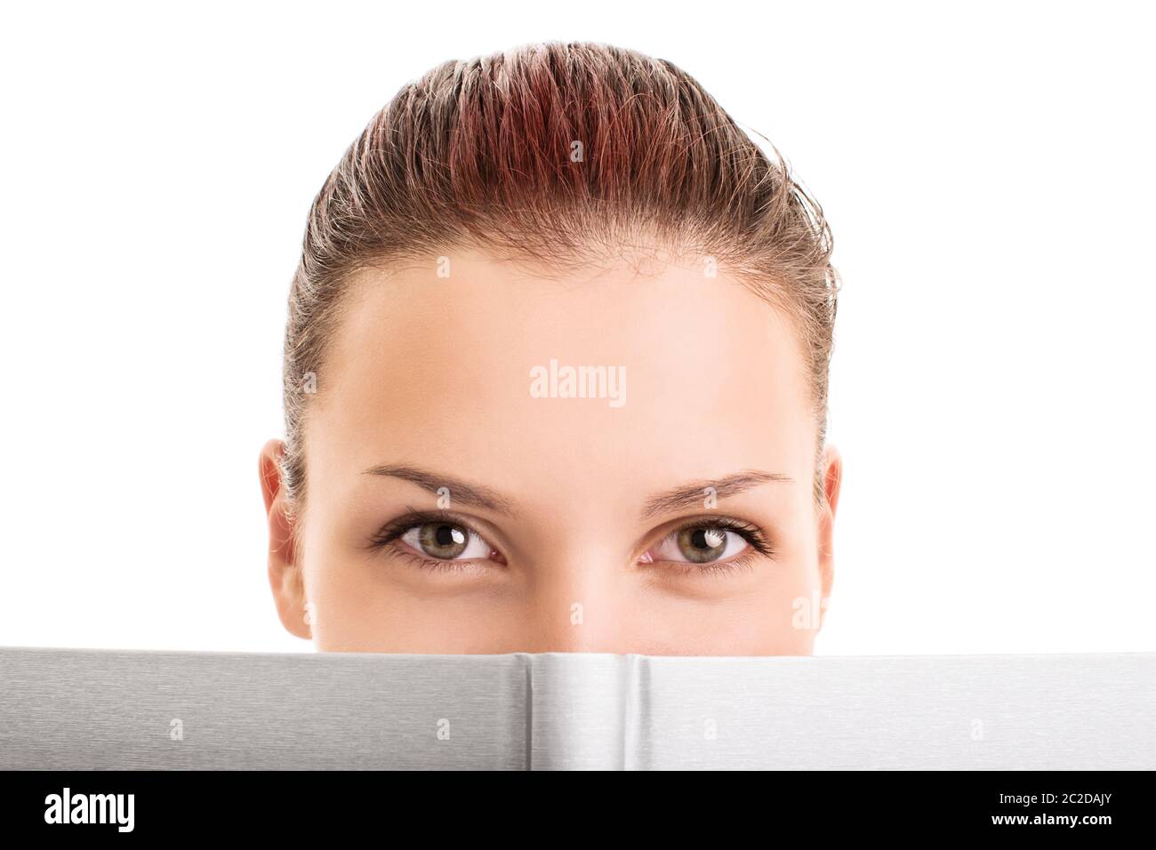 Young girl hiding her face behind a notebook, isolated on white ...