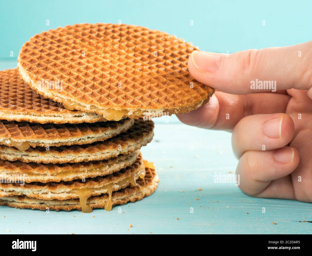 hand holding stroopwafels. Hand with caramel Dutch Waffle close up on ...