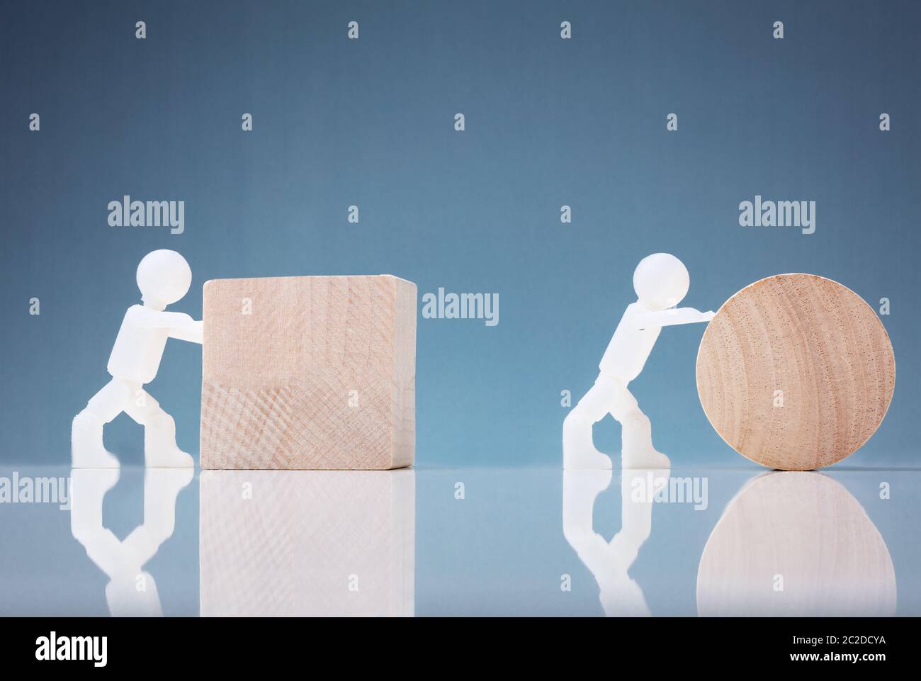 White Two Human Figure Pushing Wooden Block And Circle On Reflective ...
