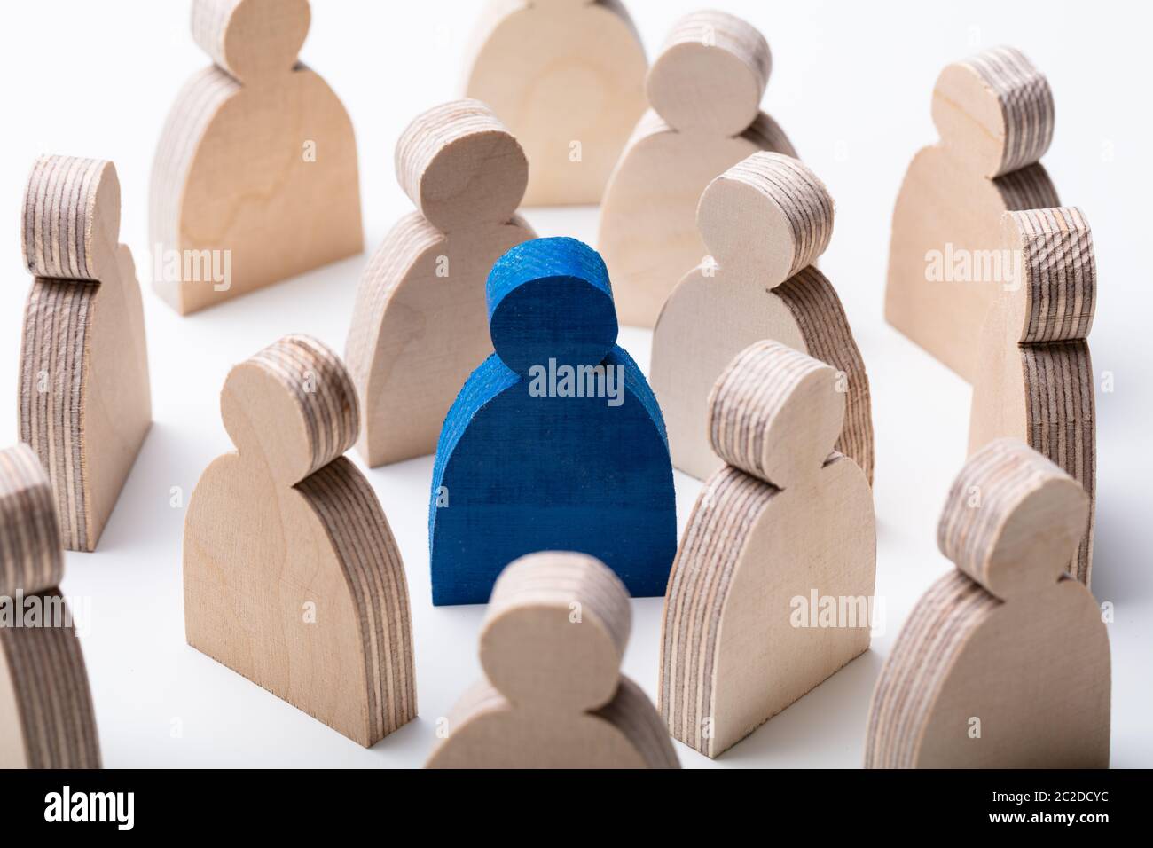 Close-up Of A Blue Human Figure Surrounded With Wooden Figures Over ...