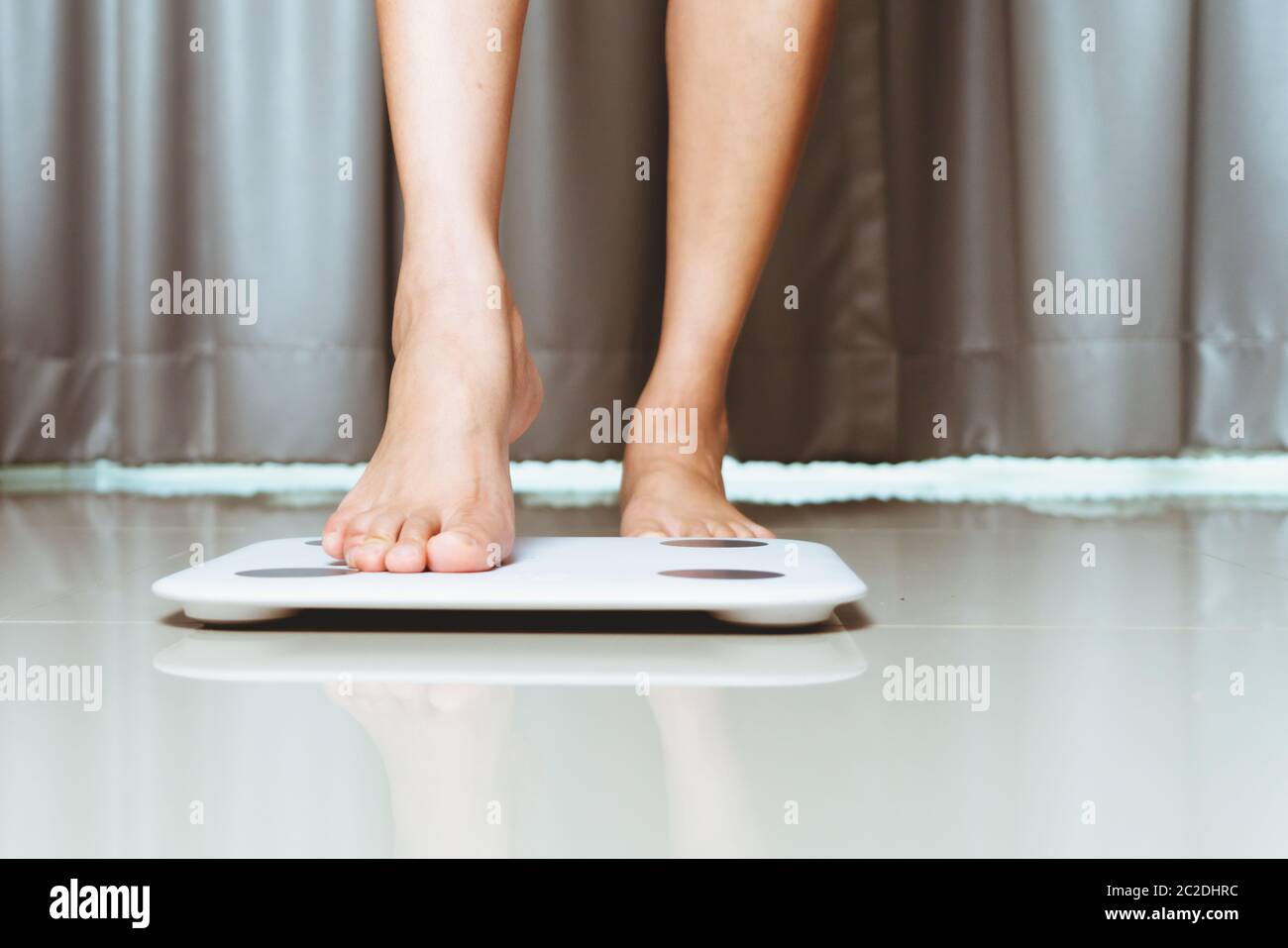 Female leg is stepping on white scales at home Stock Photo - Alamy