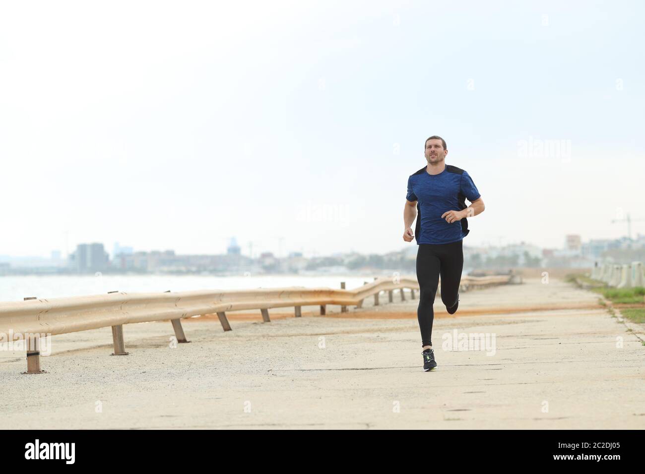 Full body portrait of a runner training running alone on the beach ...