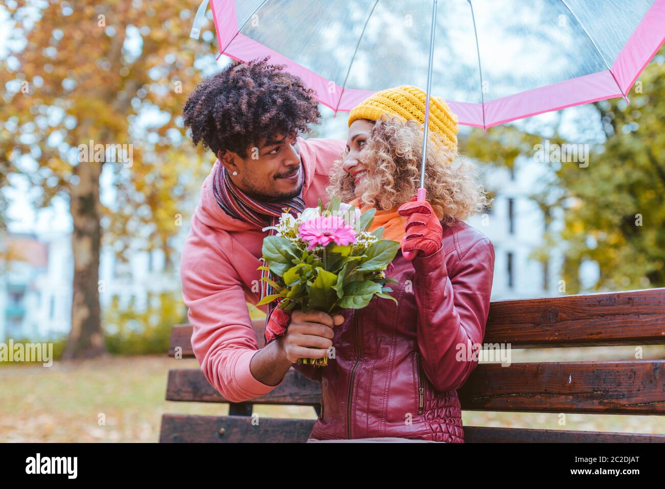 Man surprising his wife with a bouquet of flowers on a drizzly fall day ...