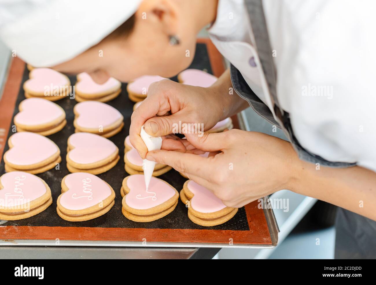 Confectioner woman writing messages and greetings on cookies Stock ...