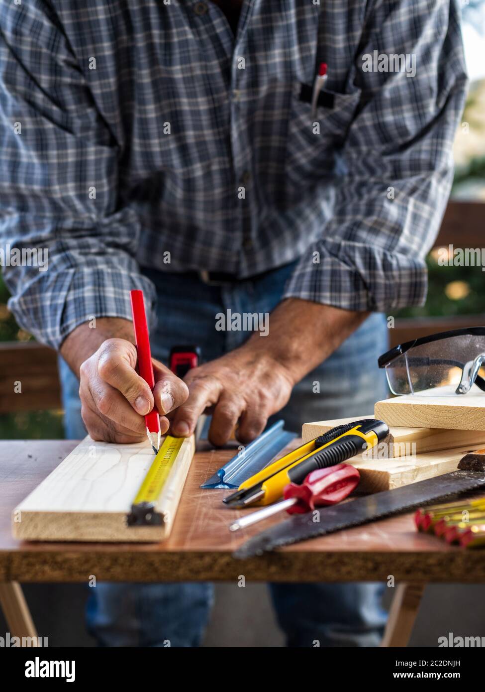 Adult craftsman carpenter with pencil and ruler tracing the cutting ...
