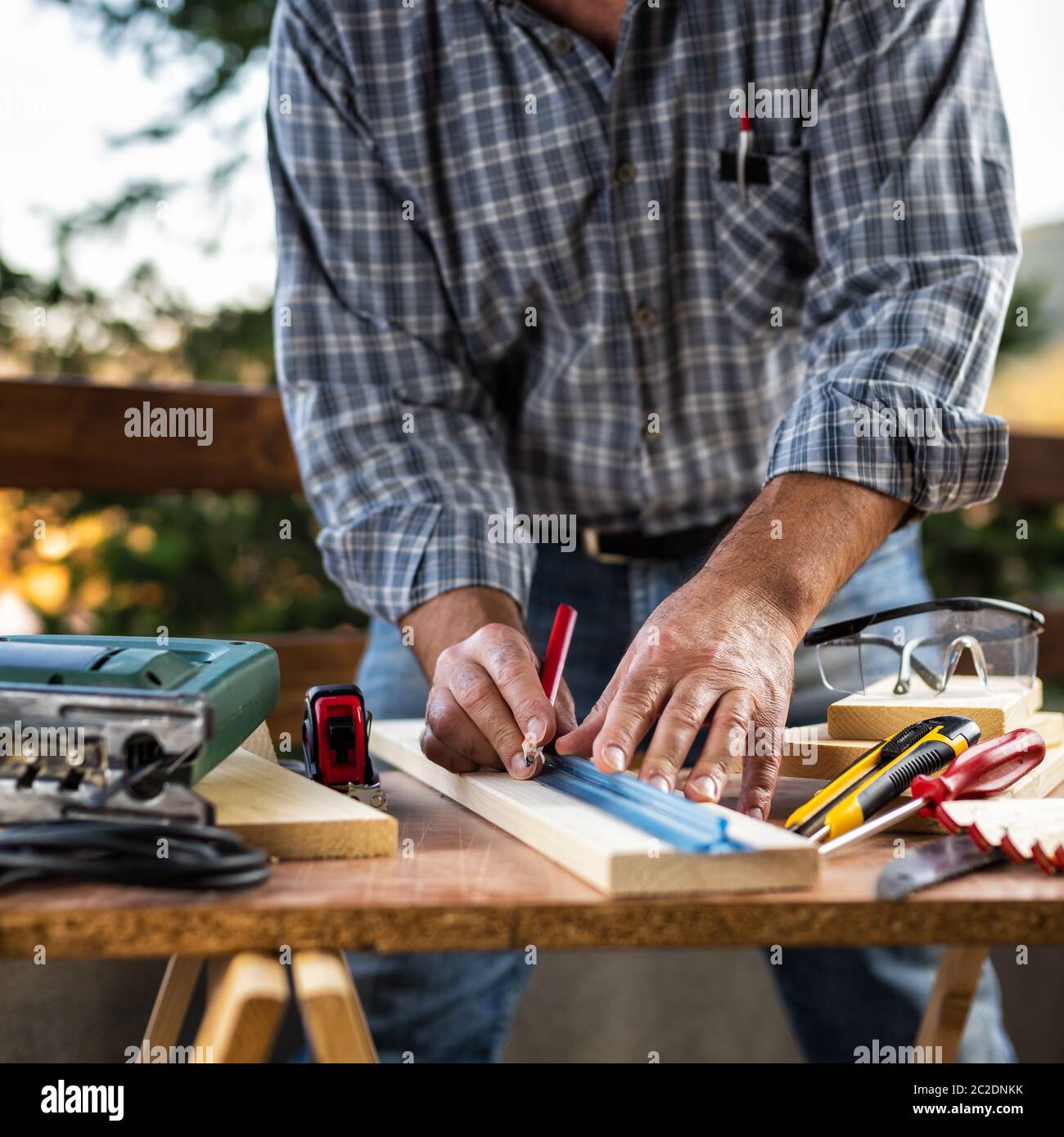 Adult craftsman carpenter with pencil and ruler tracing the cutting ...