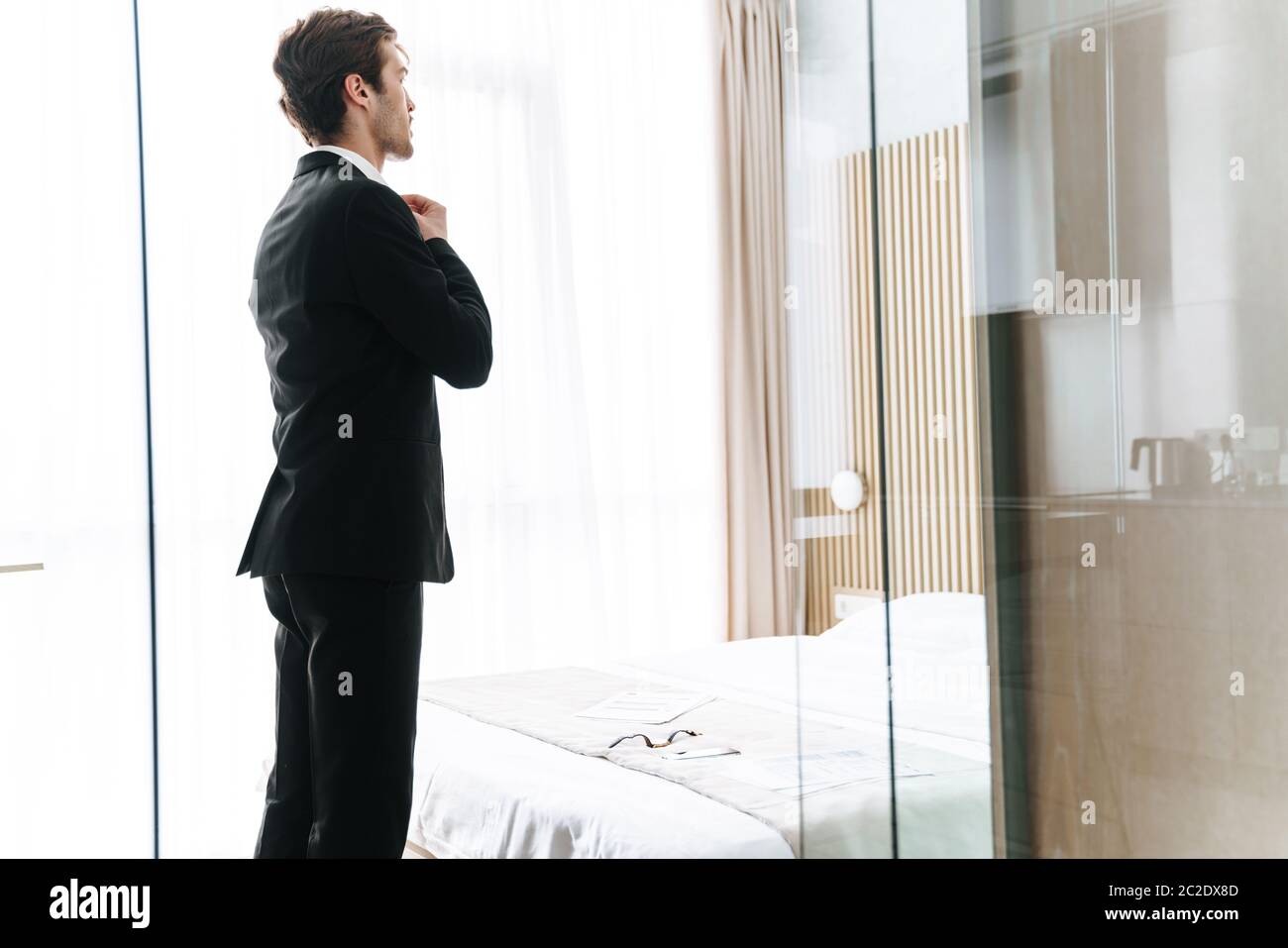 Photo of young brunette businessman wearing black suit standing in ...