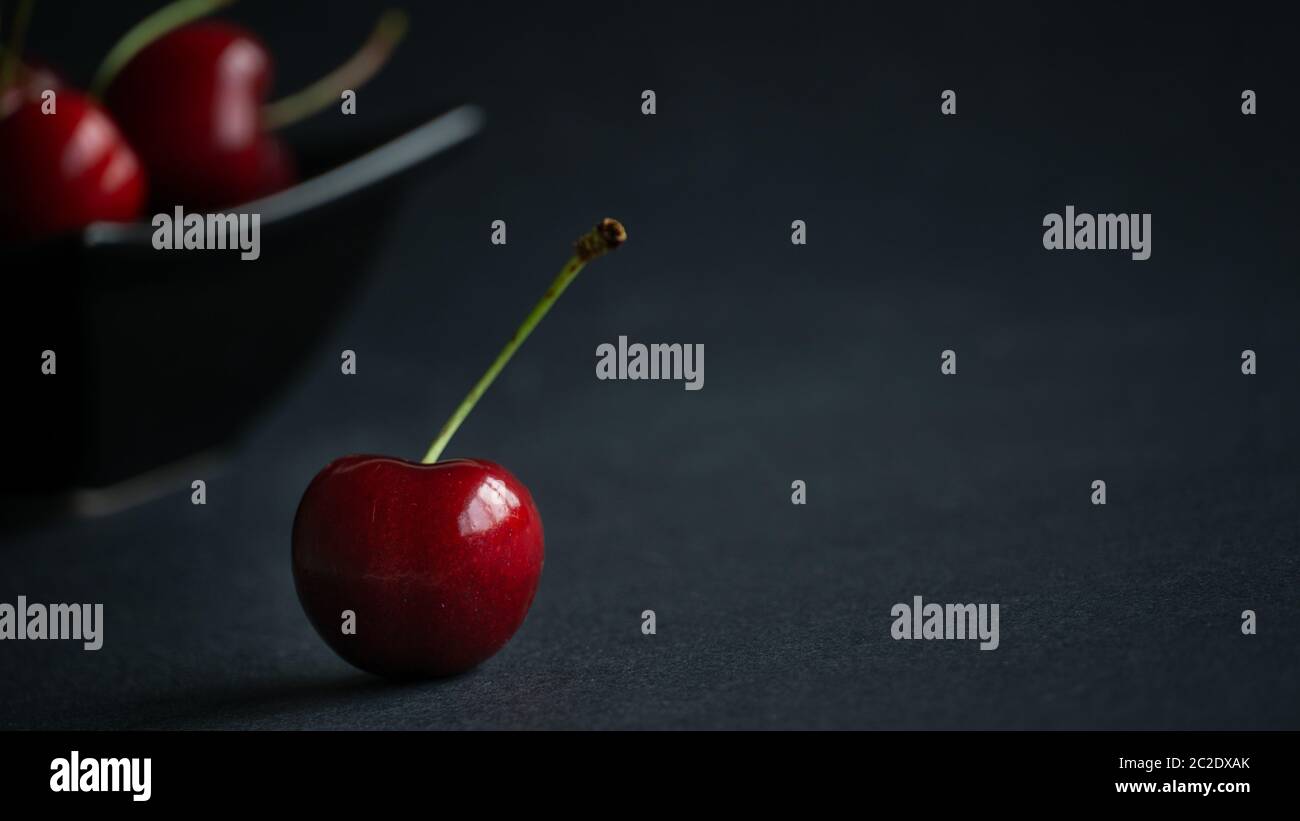Close up view of fresh fruit sweet ripe cherry in dark light and black ...