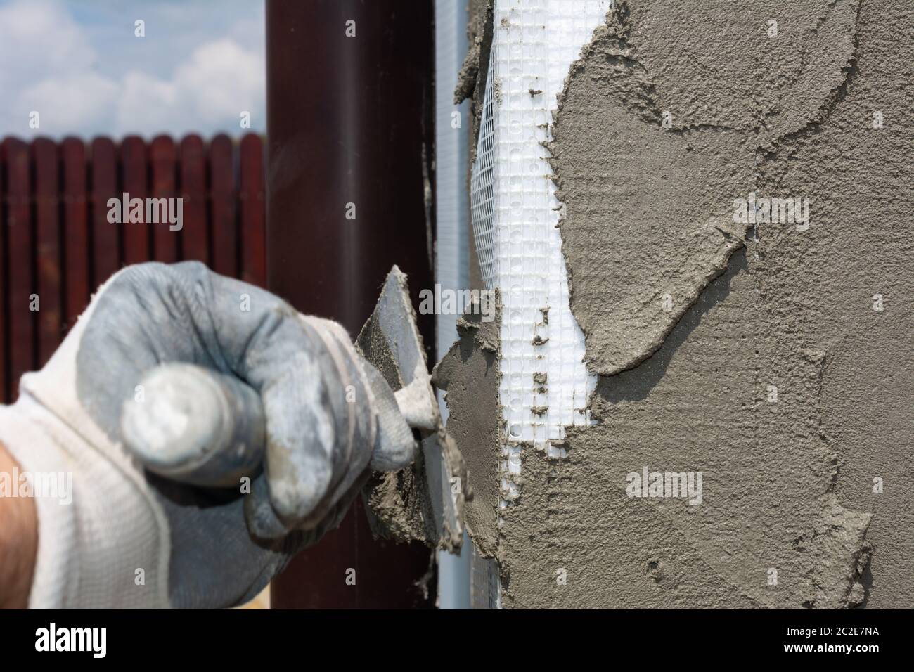 Closeup hand construction plastering wet cement on expanded polystyrene ...