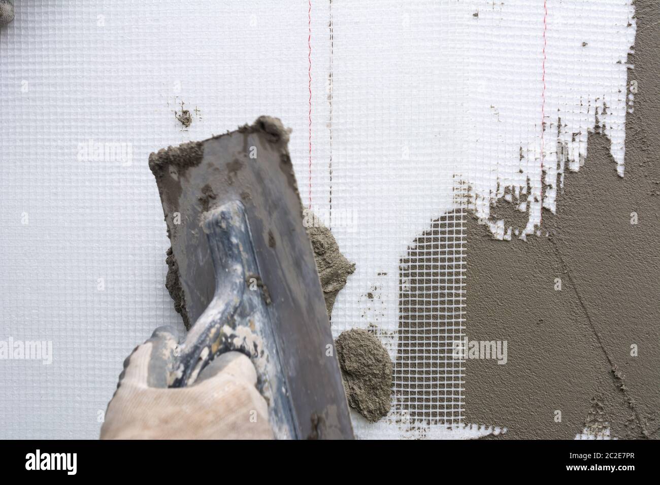 Closeup hand construction plastering wet cement on expanded polystyrene ...