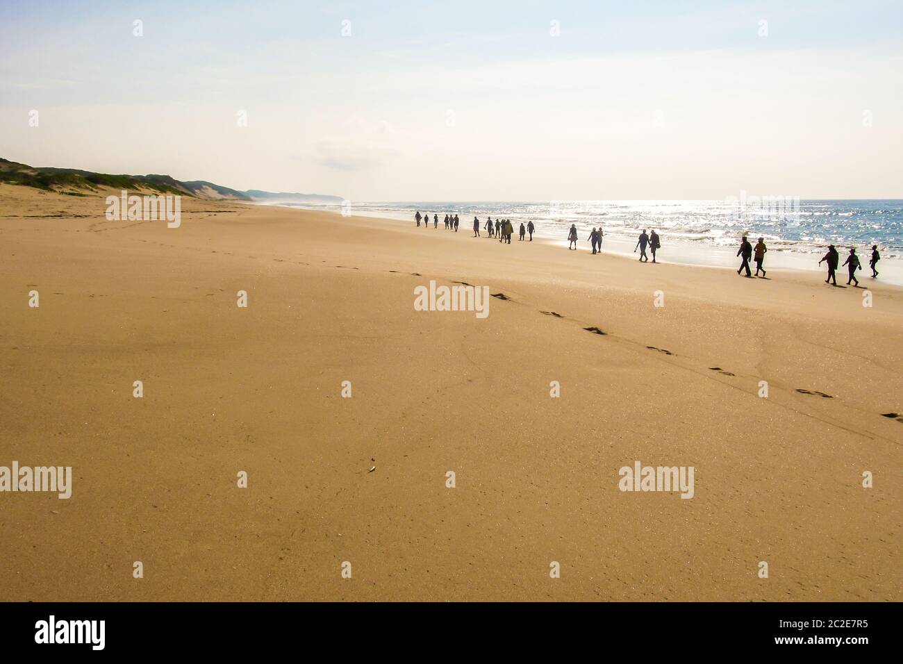Silhouettes of people walking on the wide golden beach on the Indian ...