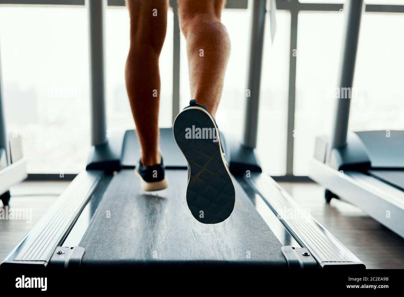 Close up male muscular feet in sneakers running on the treadmill at gym ...