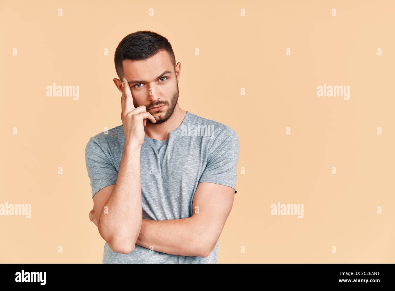 Young thoughtful man thinking and looking to camera with copy space ...
