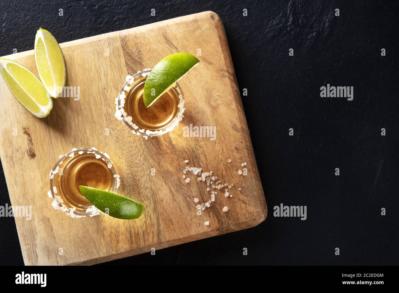 Golden tequila shots with salt and lime slices, overhead shot on black ...