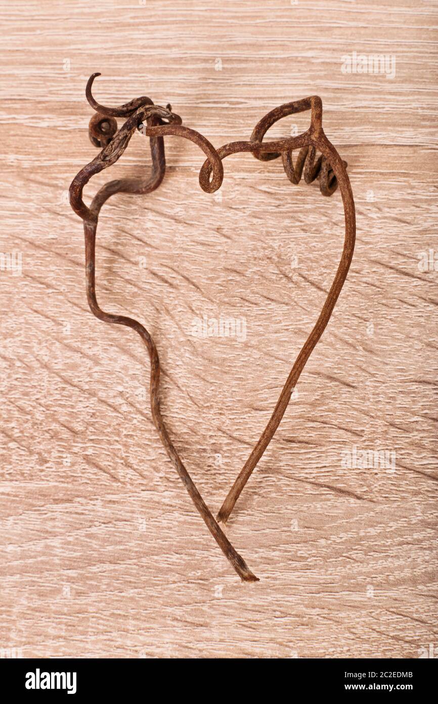 Withered heart. Heart shape made of vines on textured wooden background ...