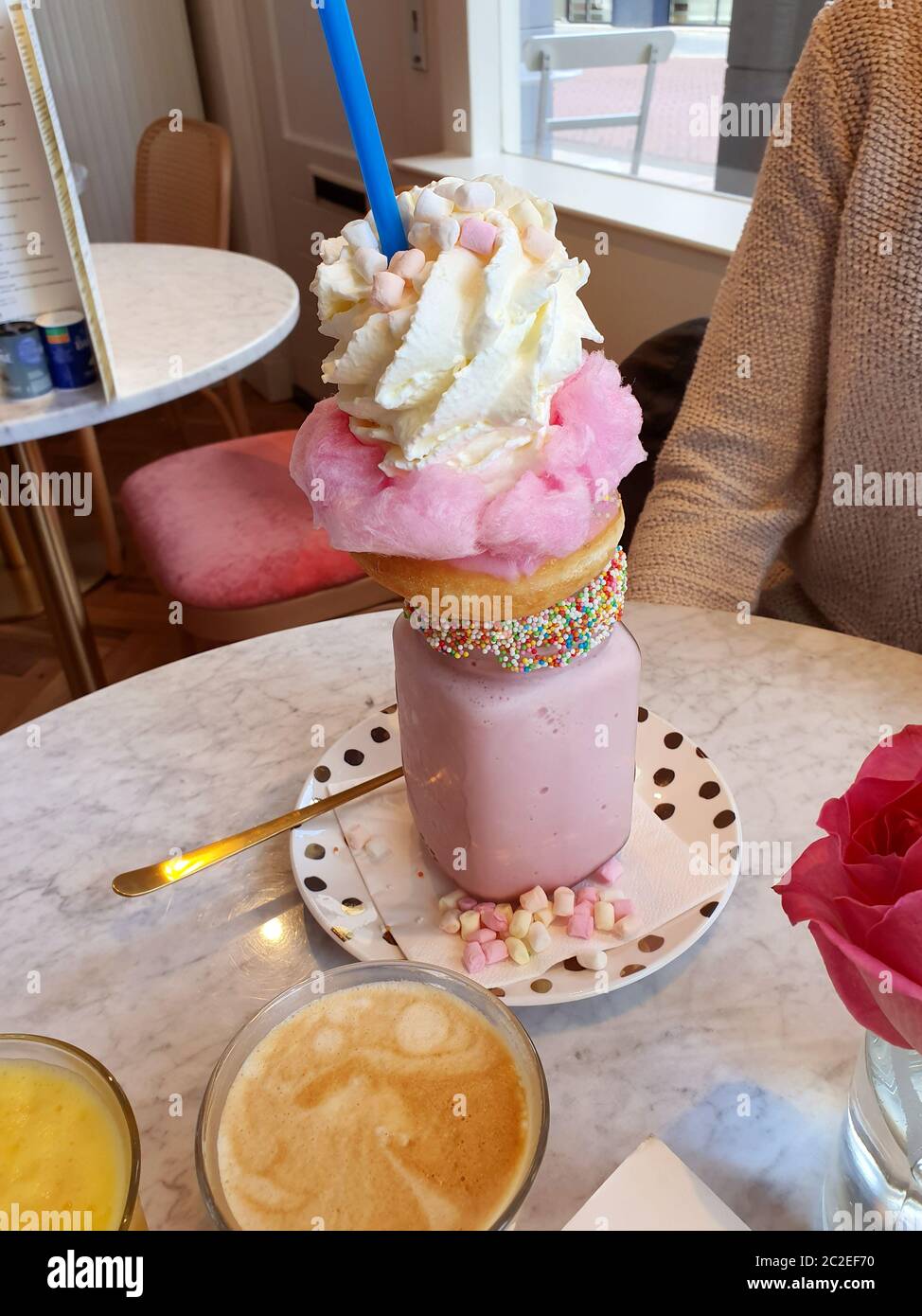 Pink strawberry freakshake with sweets, donuts and wipped cream in cafe ...