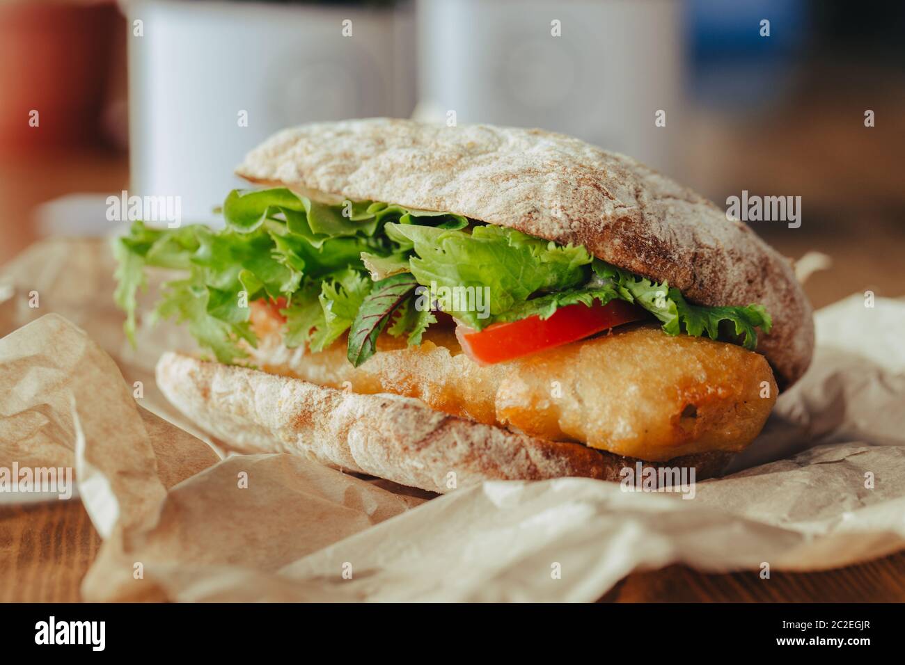 fried fish on a bun with lettuce, tomato street food Stock Photo - Alamy
